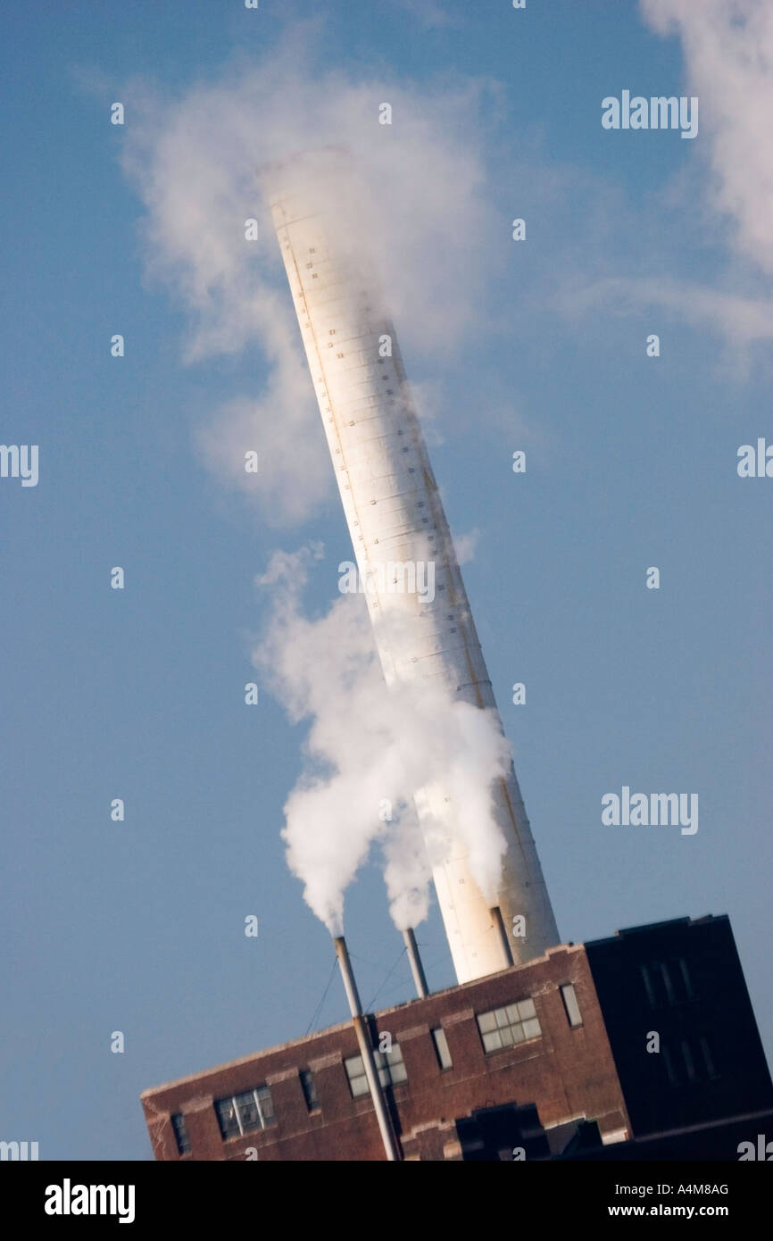 A tall smokestack rises above a brick factory building Stock Photo - Alamy