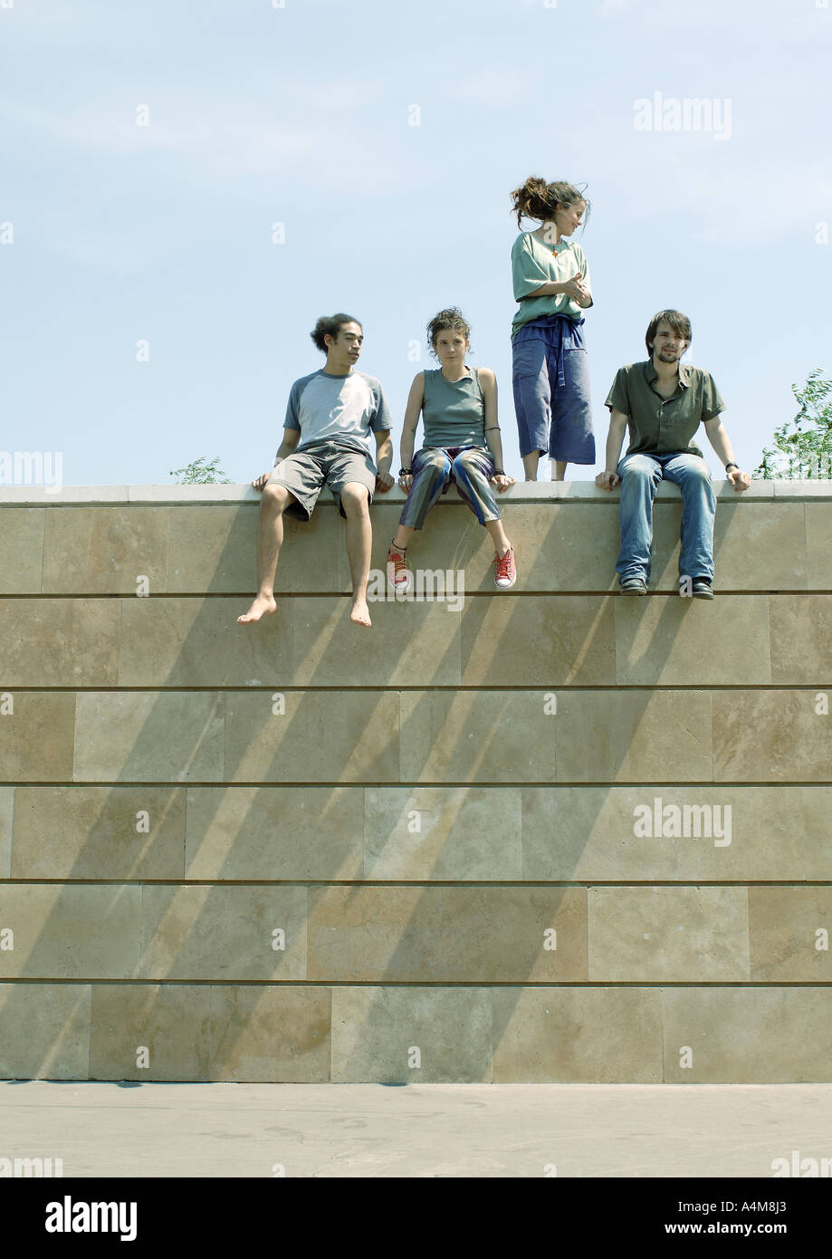 Young people on top of wall Stock Photo - Alamy