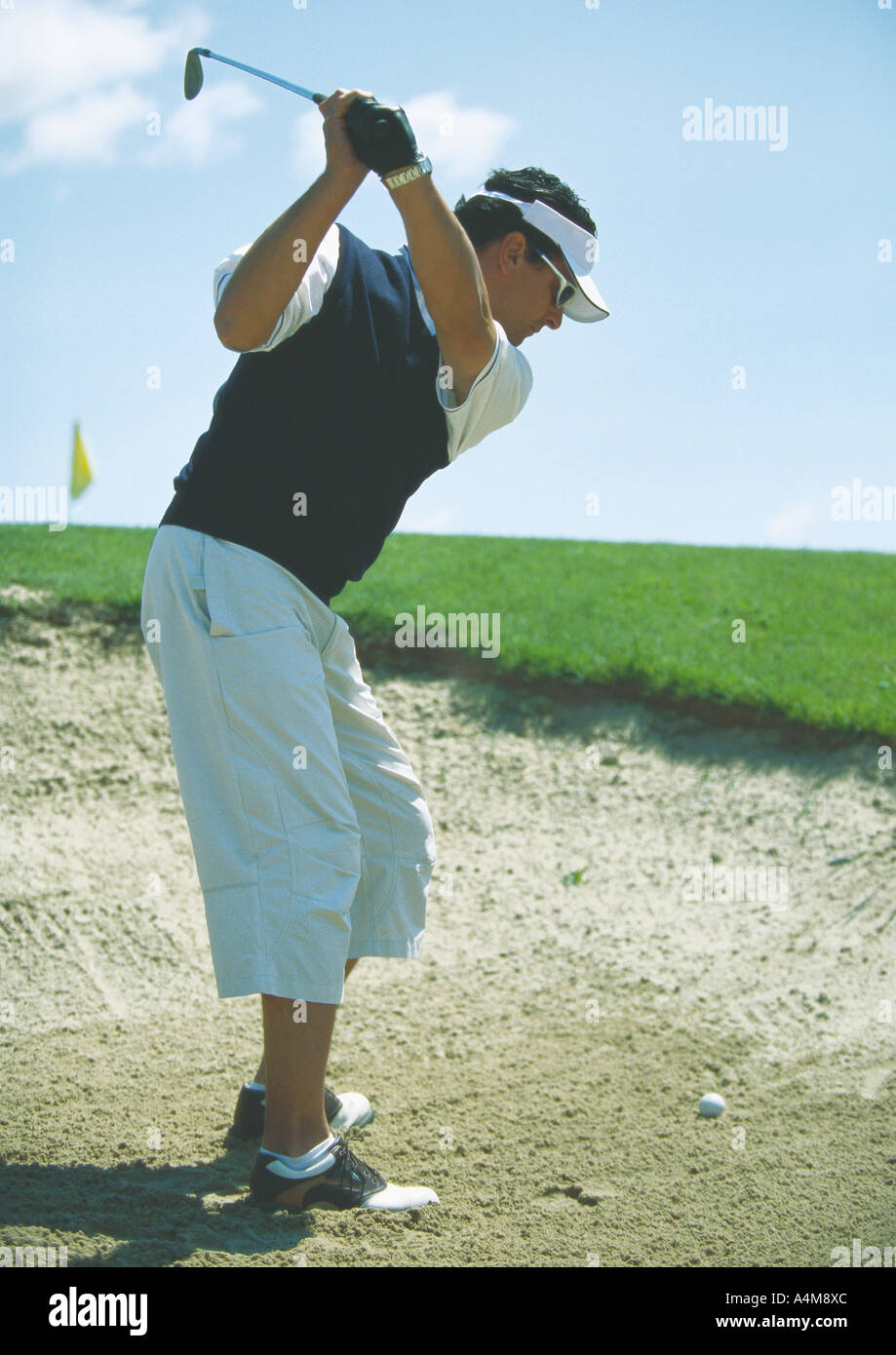 Golfer swinging in sand trap Stock Photo - Alamy