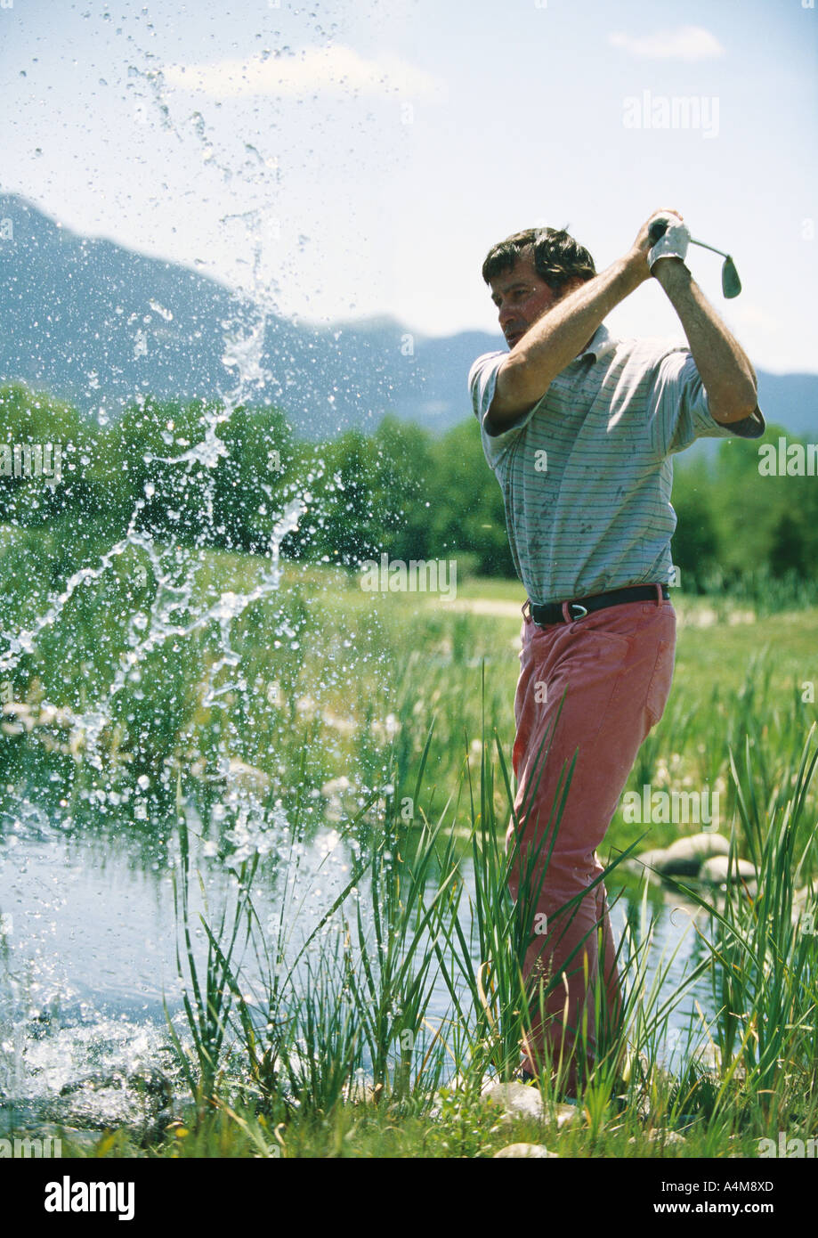 Golfer swinging in water Stock Photo - Alamy