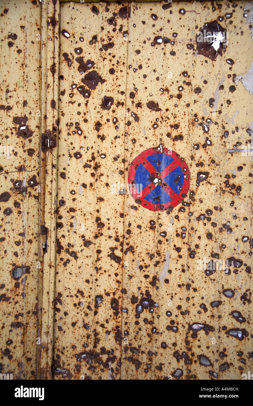 No Parking / No Stopping sign painted on damaged metal gate. Mostar ...