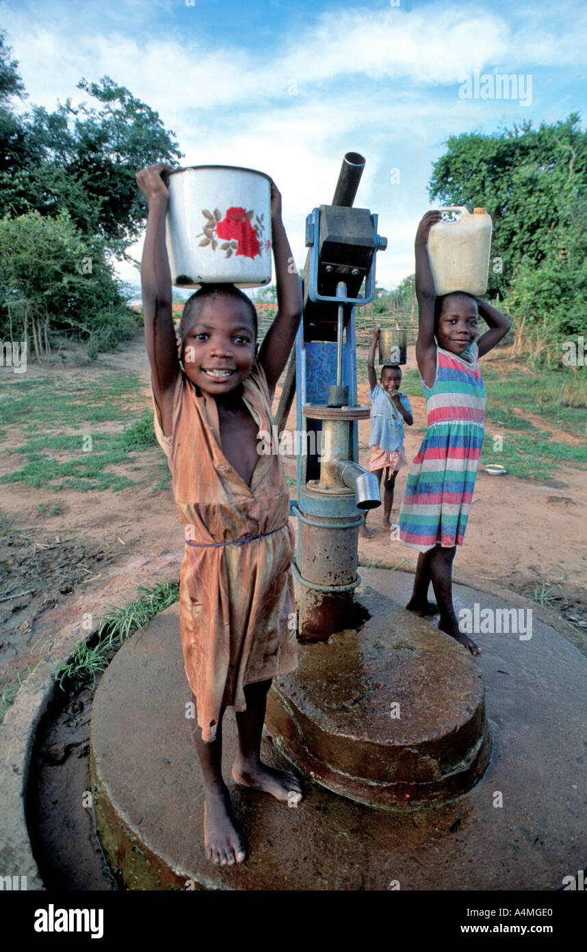 Tonga girls carrying water pots on their heads at the water pump ...