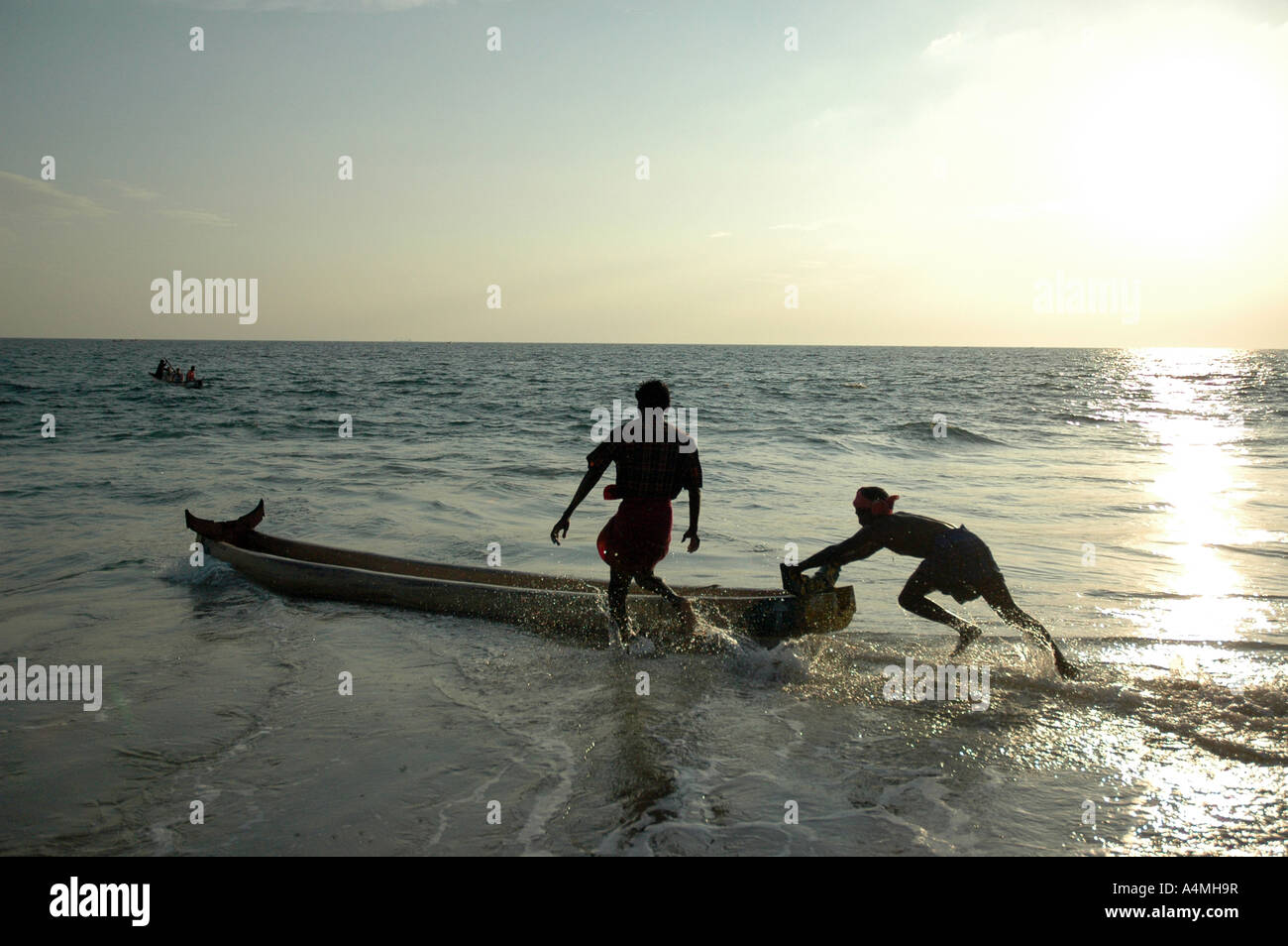 Fishermen pushing boat into water Kerala India Stock Photo - Alamy