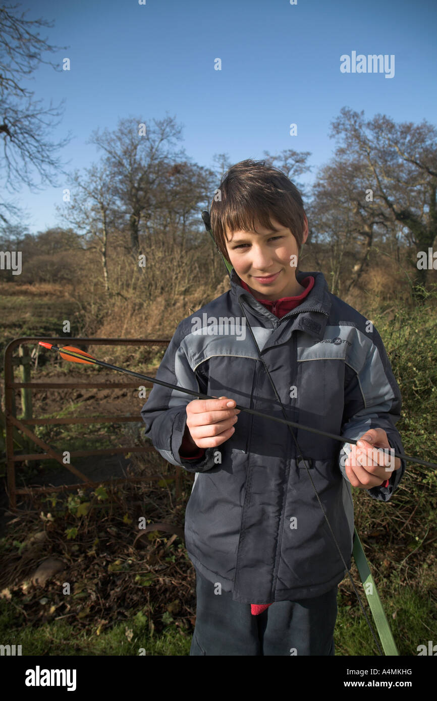 Boy standing outside in winter smiling at camera holding bow and arrow ...