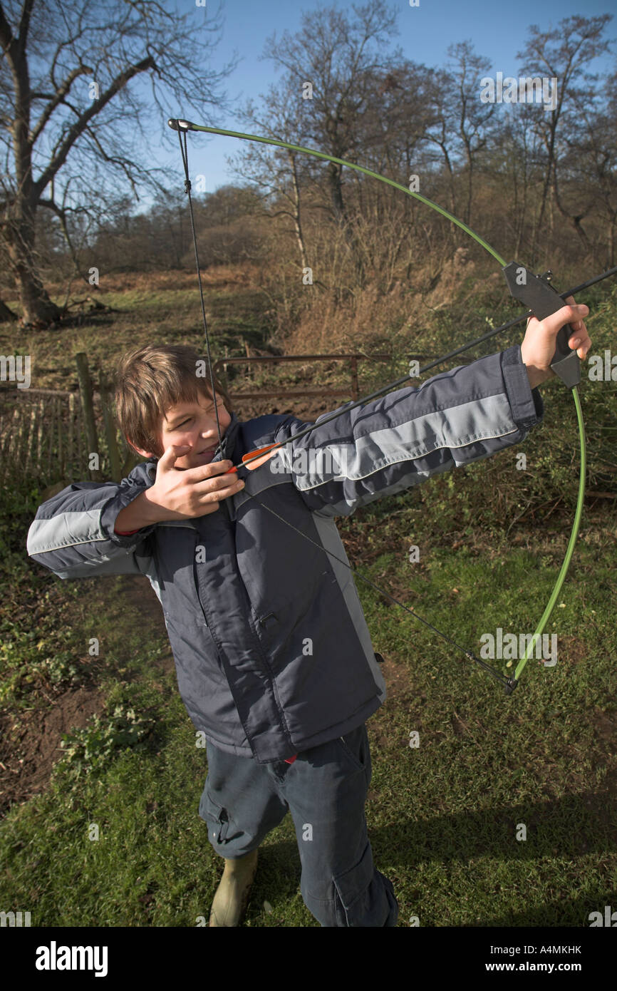 Boy firing an arrow from his bow holding his bow and pulling hard Stock ...