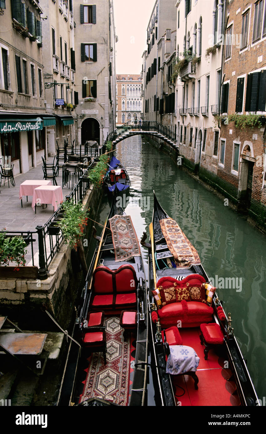 EUROPE ITALY VENICE Moored gondolas besides canalside cafe restaurant ...