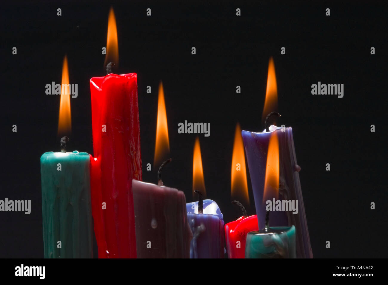 Multi colored candles burning against black reflective background Stock ...