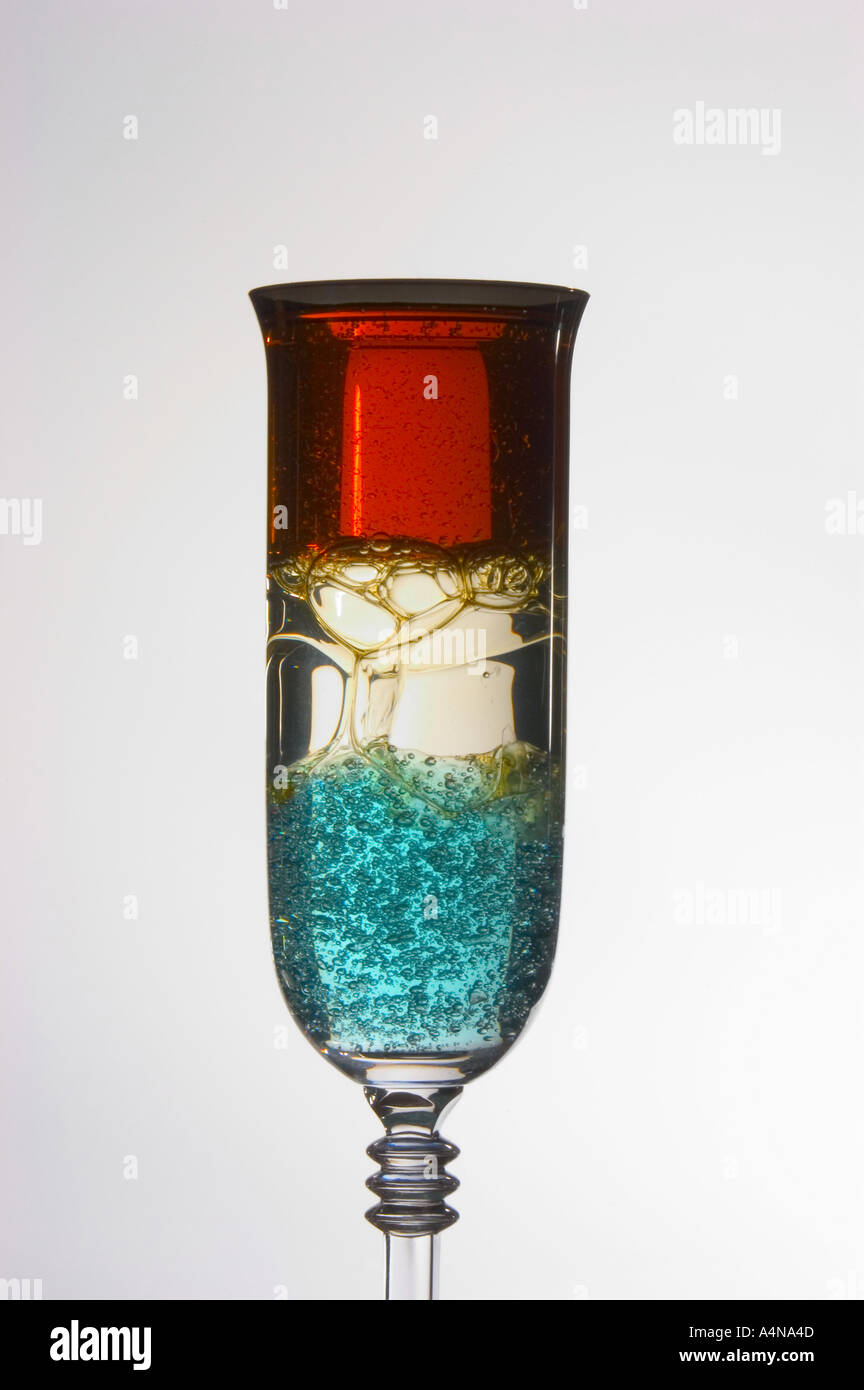 Three layers of colored liquid of different densities in small glass ...