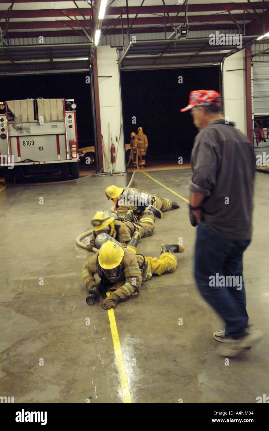 Firefighter trainees practice their skills dragging a hoseline while ...