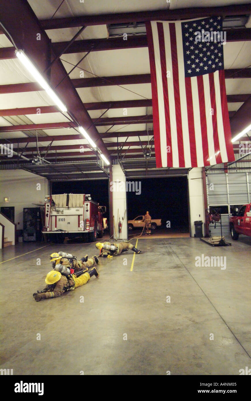 Firefighter trainees practice their skills dragging a hoseline while ...