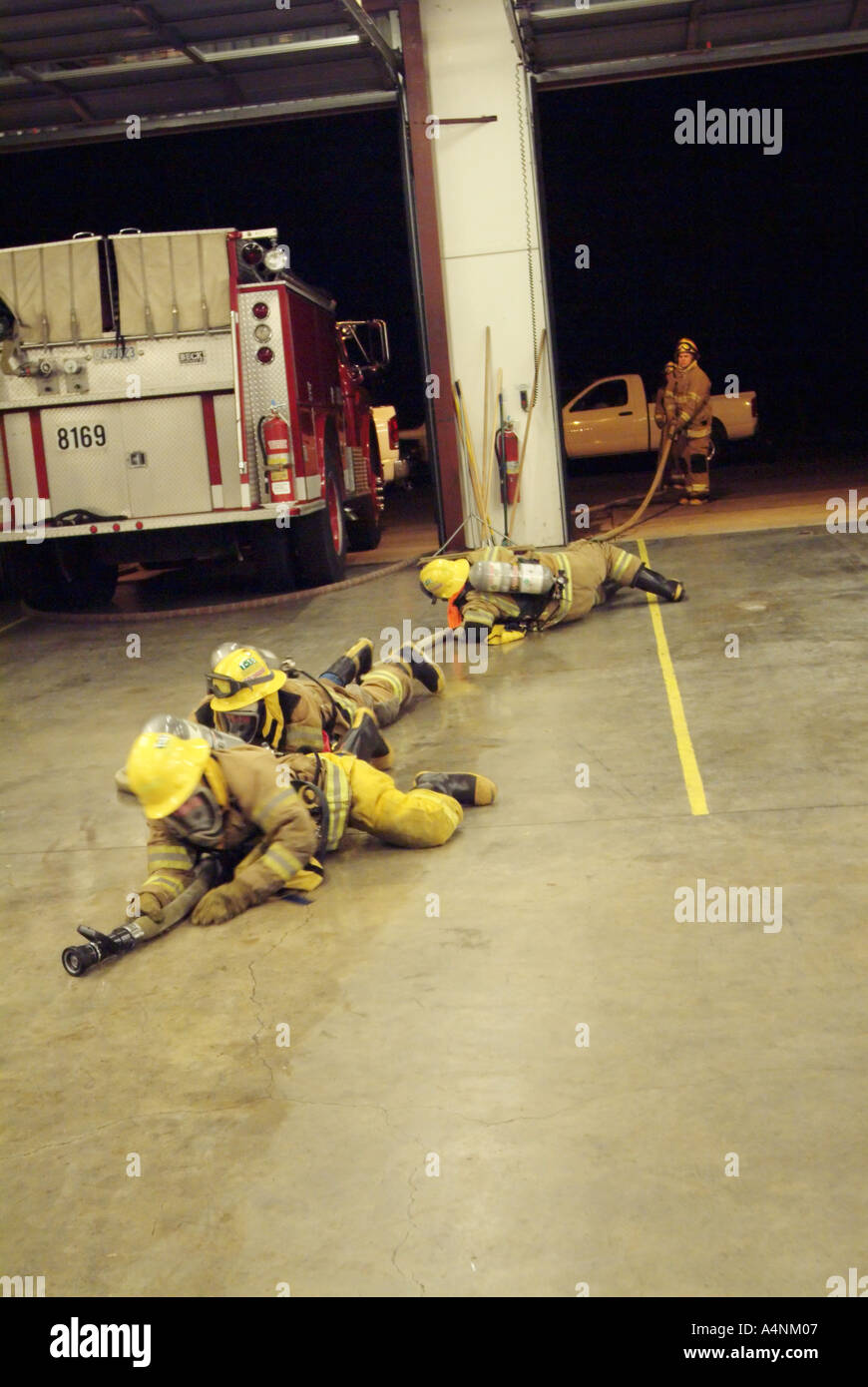 Firefighter trainees practice their skills dragging a hoseline while ...