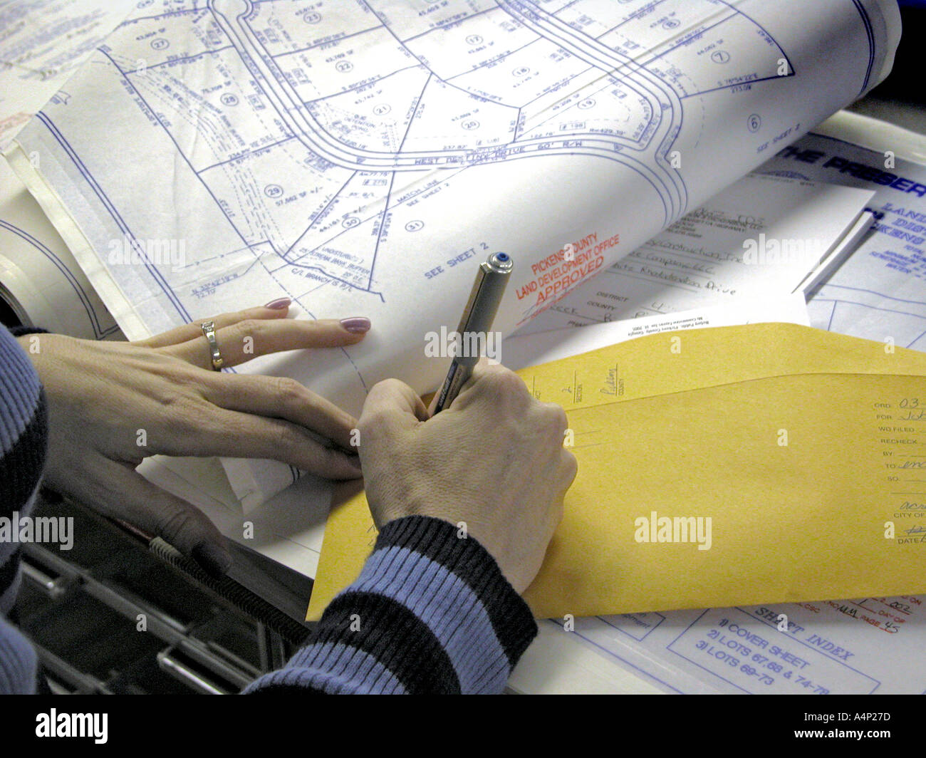 Female woman title examiner working on back chain via plot maps in ...