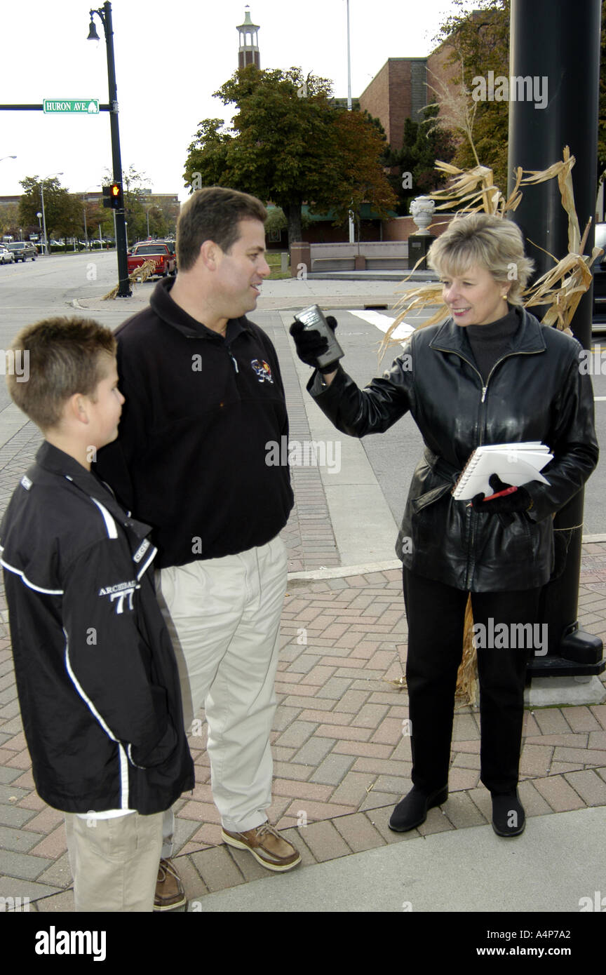 Female reporter does an in the street interview with a father and son ...