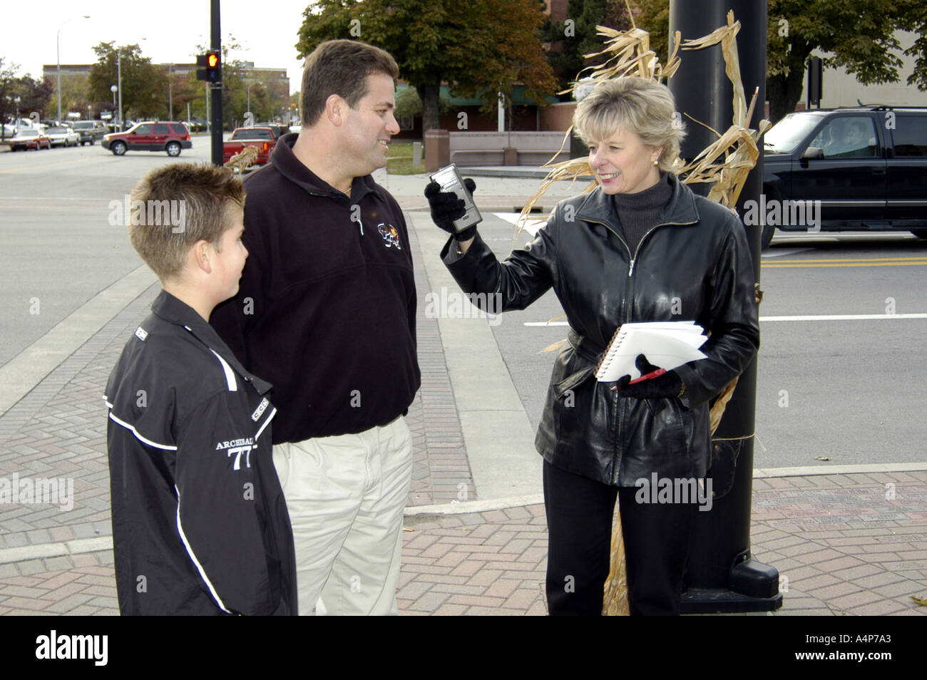 Female reporter does an in the street interview with a father and son ...