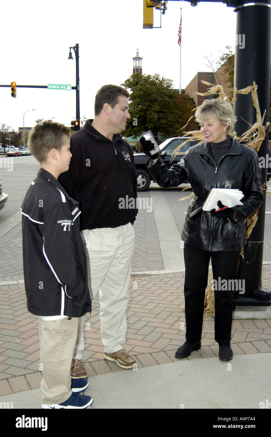 Female reporter does an in the street interview with a father and son ...