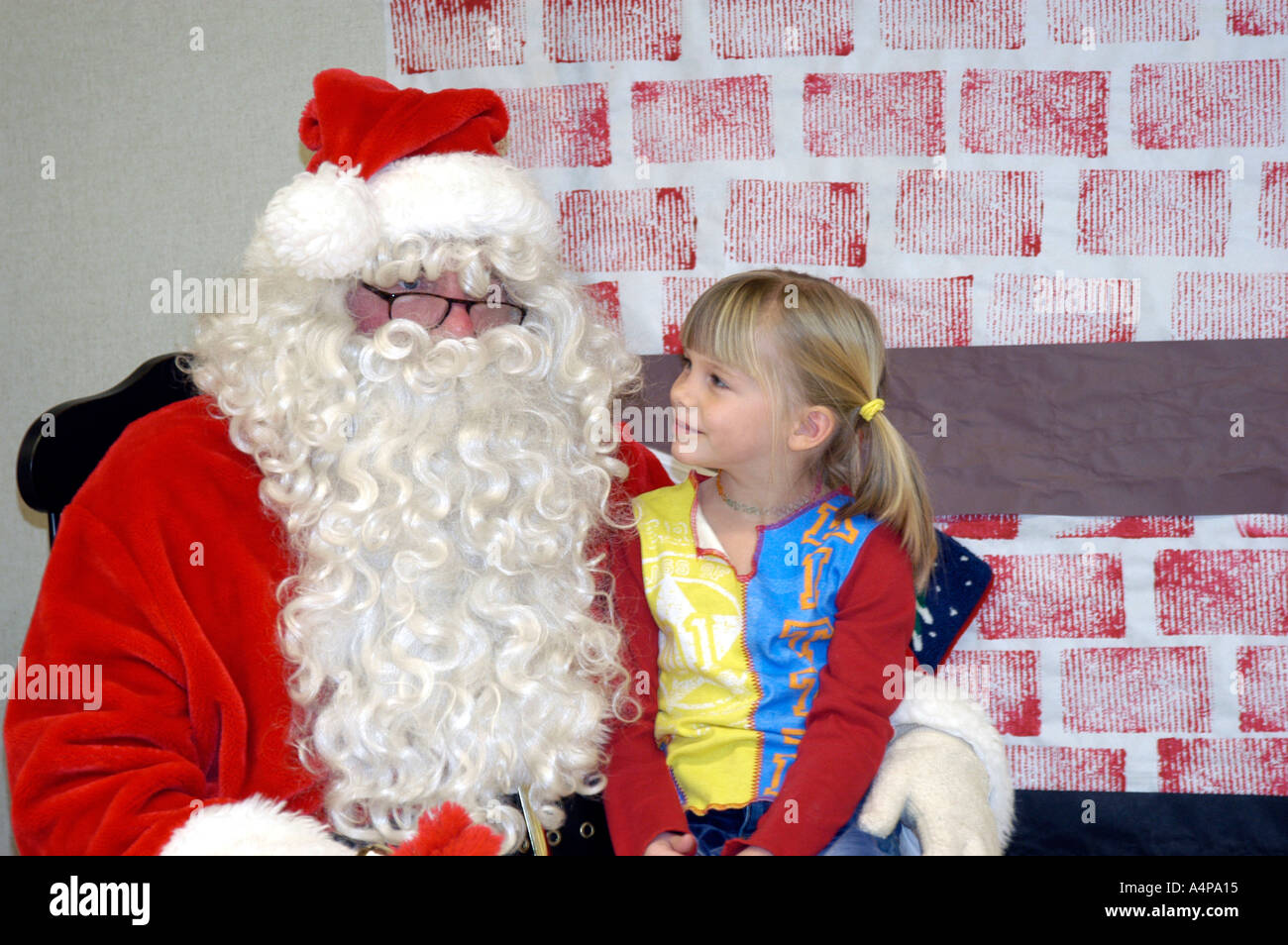 Small girl sits on the lap of Santa Claus to communicate Christmas ...