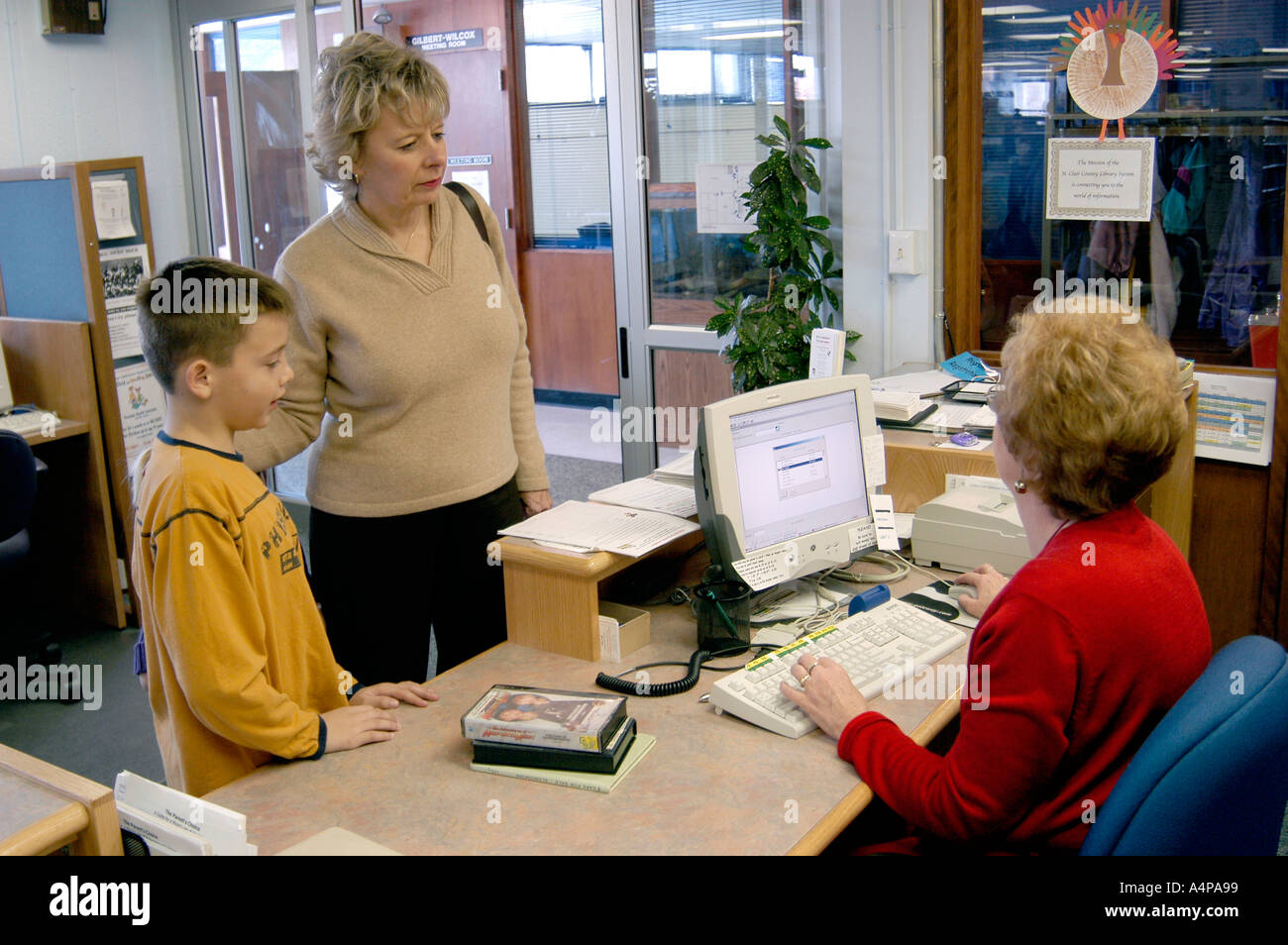 Children with grandmother checks out books from a public library Stock ...