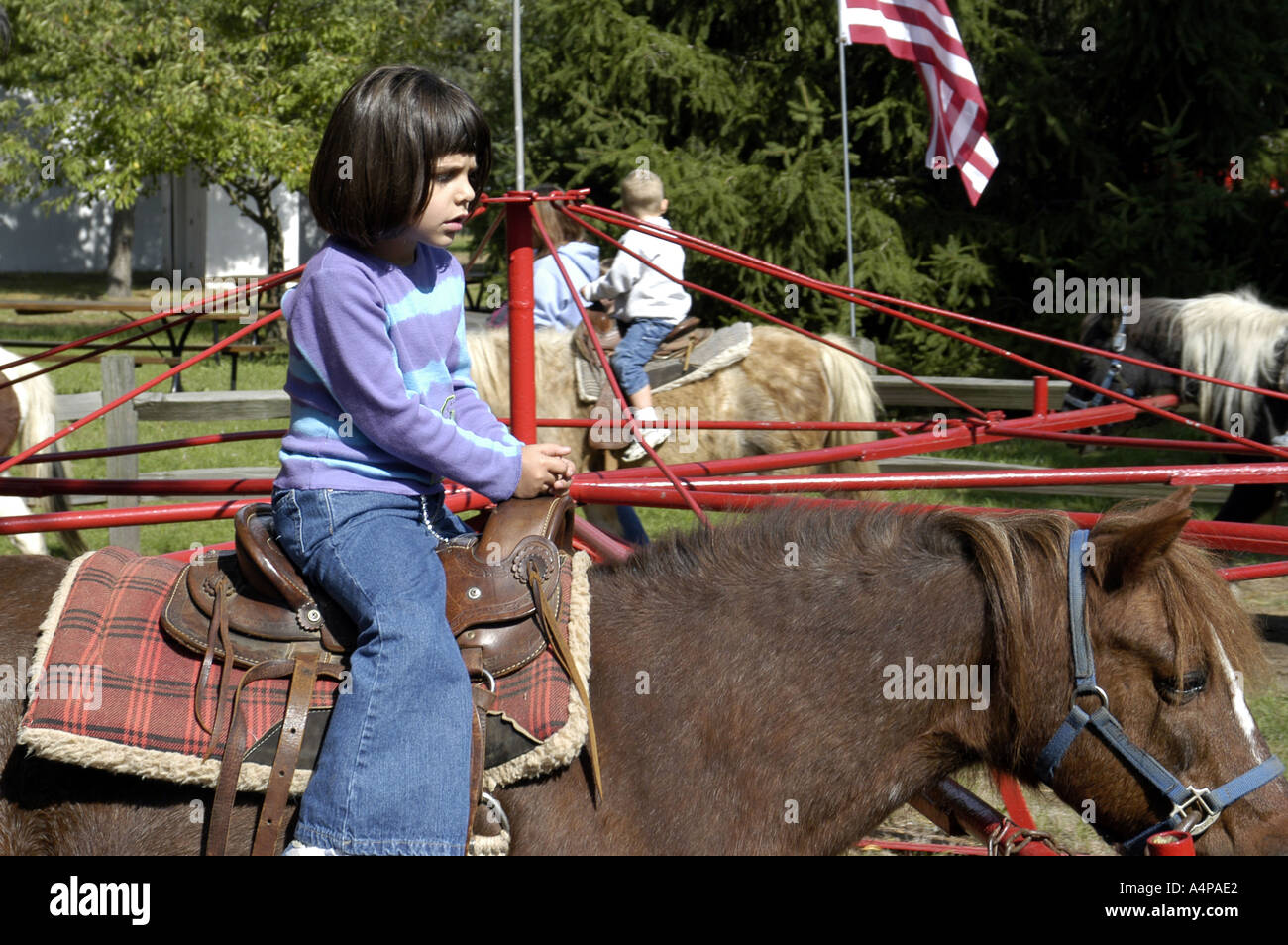 Kids ride ponies horses at a children farm Michigan Stock Photo - Alamy