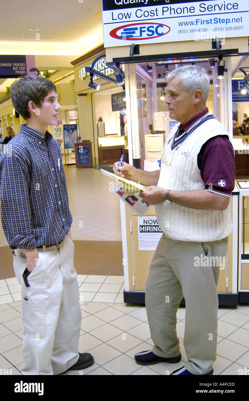 Male takes survey of shoppers in a large shopping mall surveying Stock ...