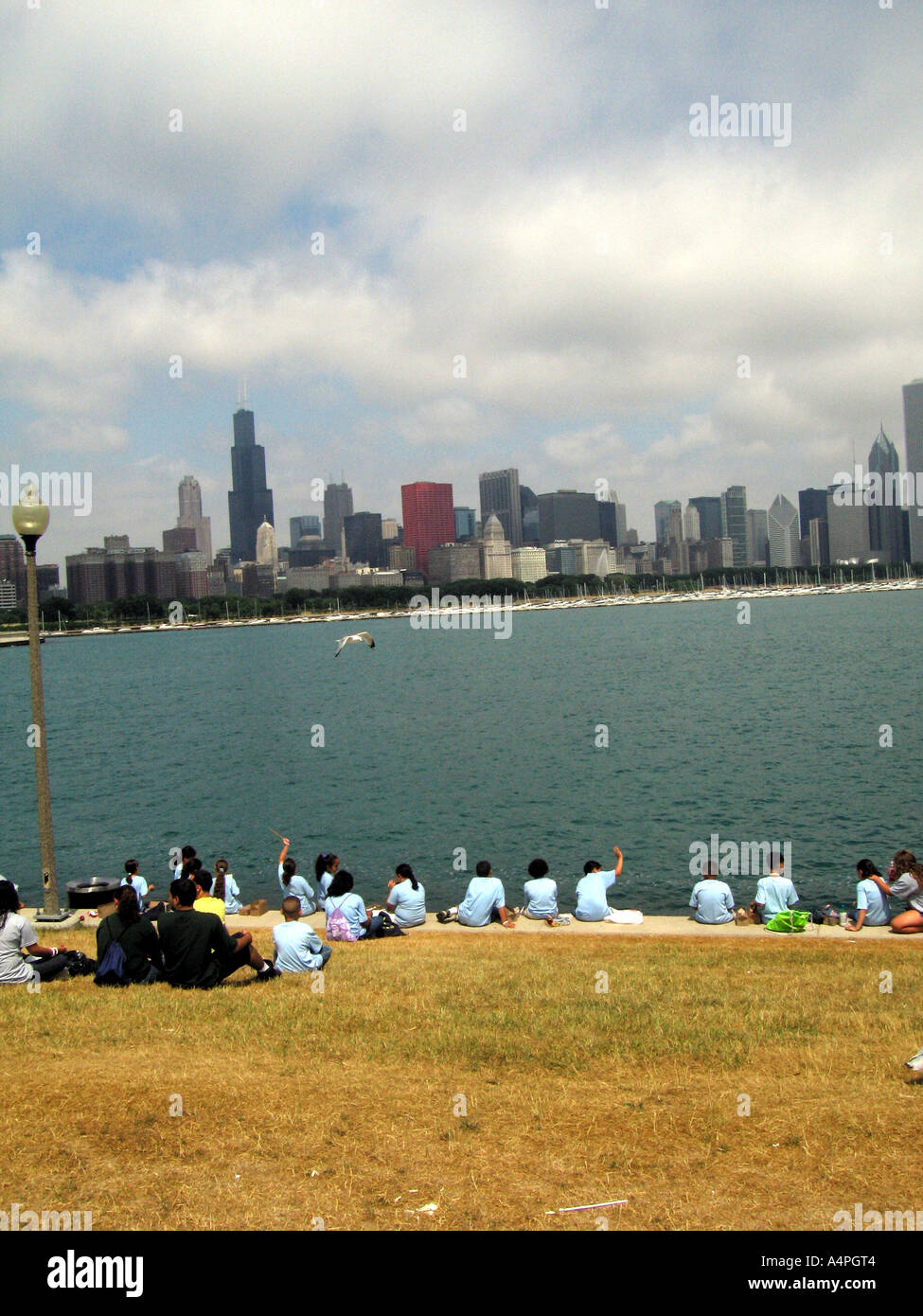 School children sitting on the edge of the lake overlooking Chicago ...