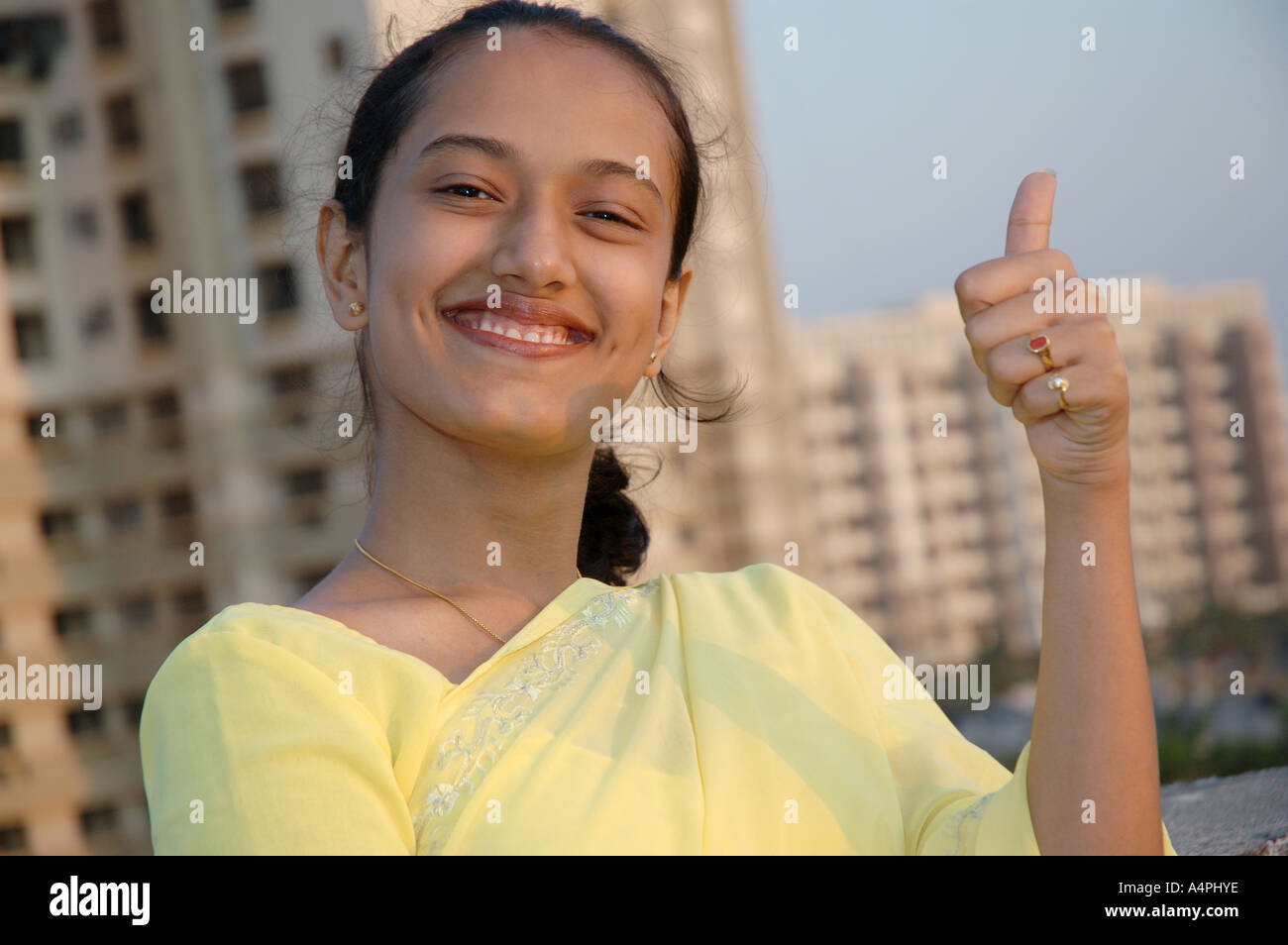 ANG77734 Young South Asian Indian girl smiling showing thumbs up sign ...