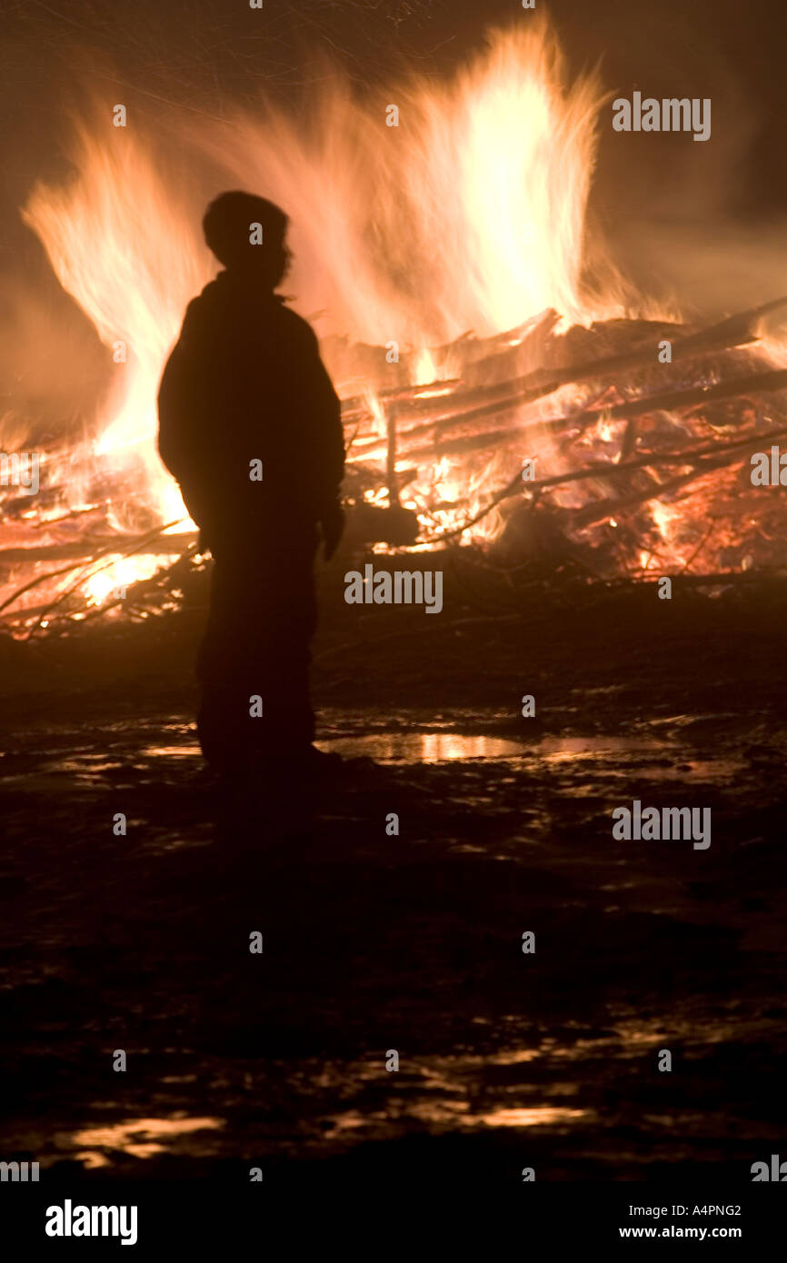 Silhouette of a person standing near a fire at night Stock Photo - Alamy