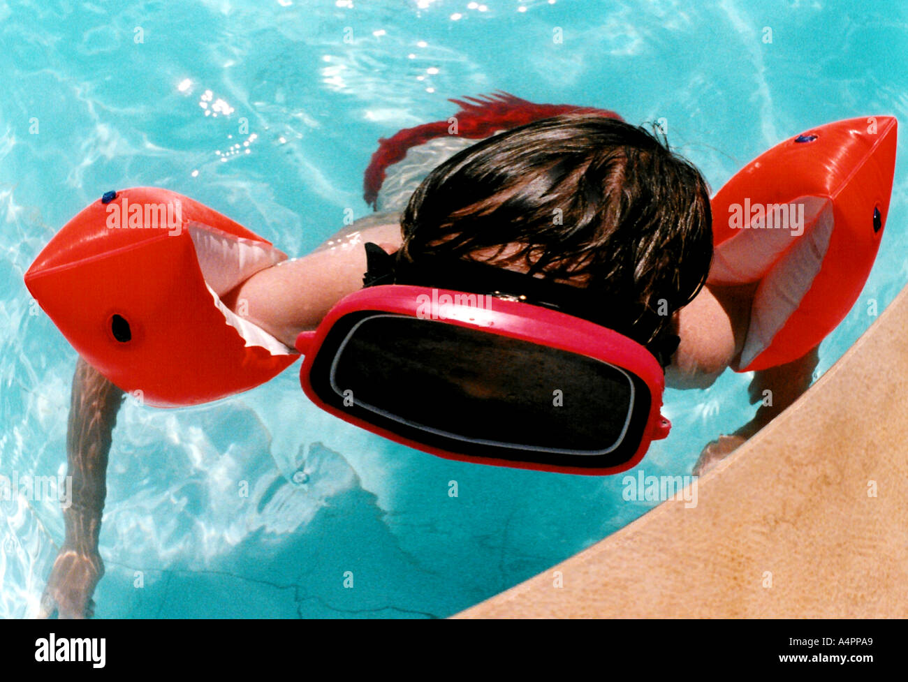 Boy swimming wearing face mask and arm bands in swimming pool Stock ...