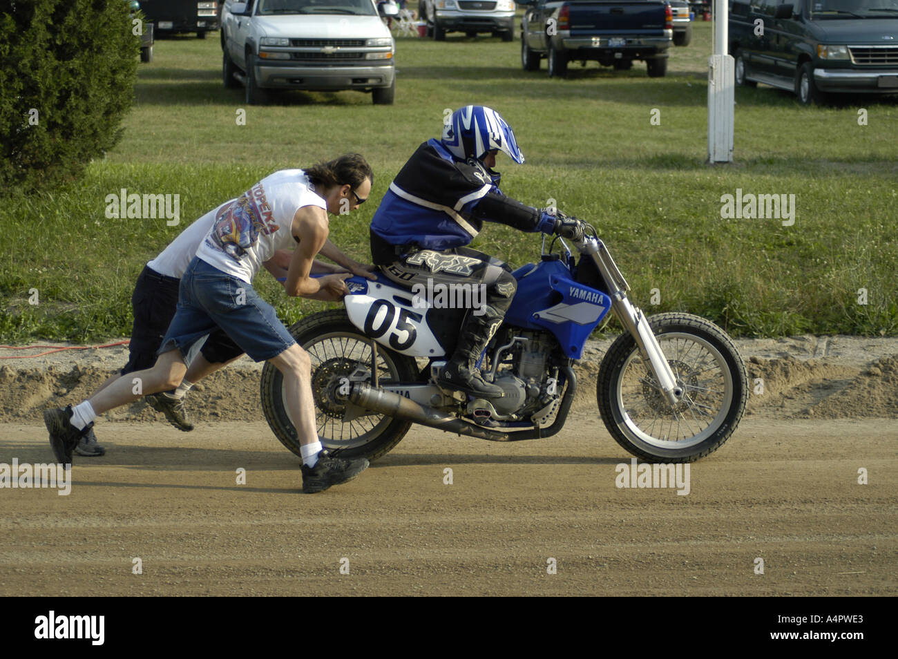 Dirt track racing 2 caucasion men push racer on blue motorcycle 05 to ...