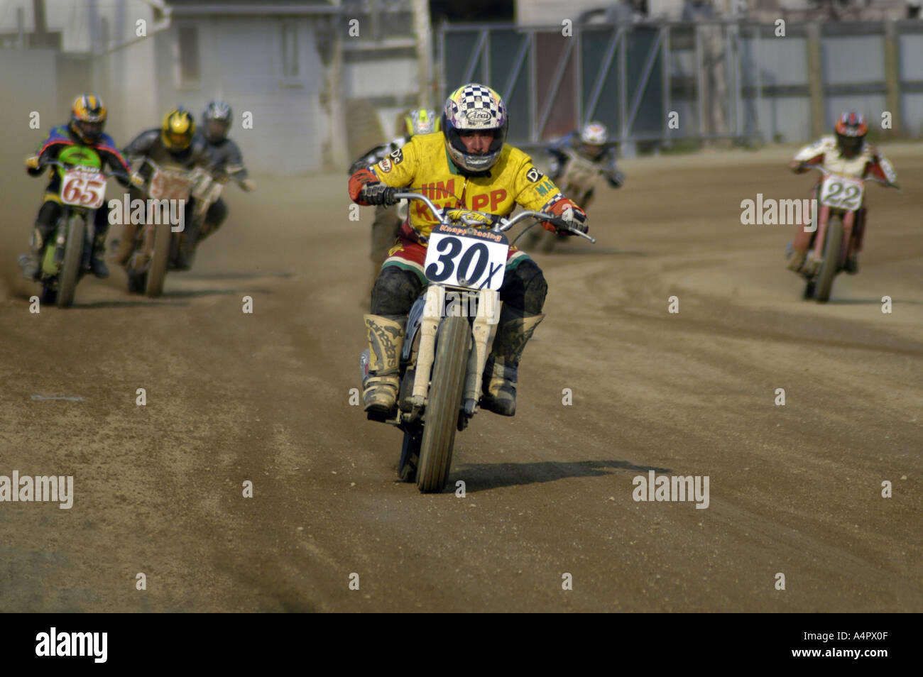 Pack of riders led by 30 vies for position through corner of dirt track ...
