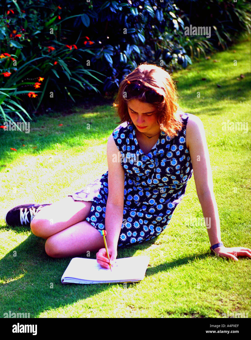 Girl on lawn with book Stock Photo - Alamy