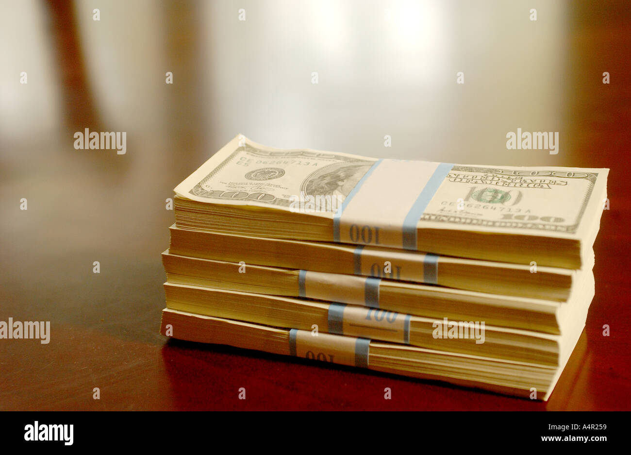 Color image of a banded stack of US currency sitting on a wood table ...