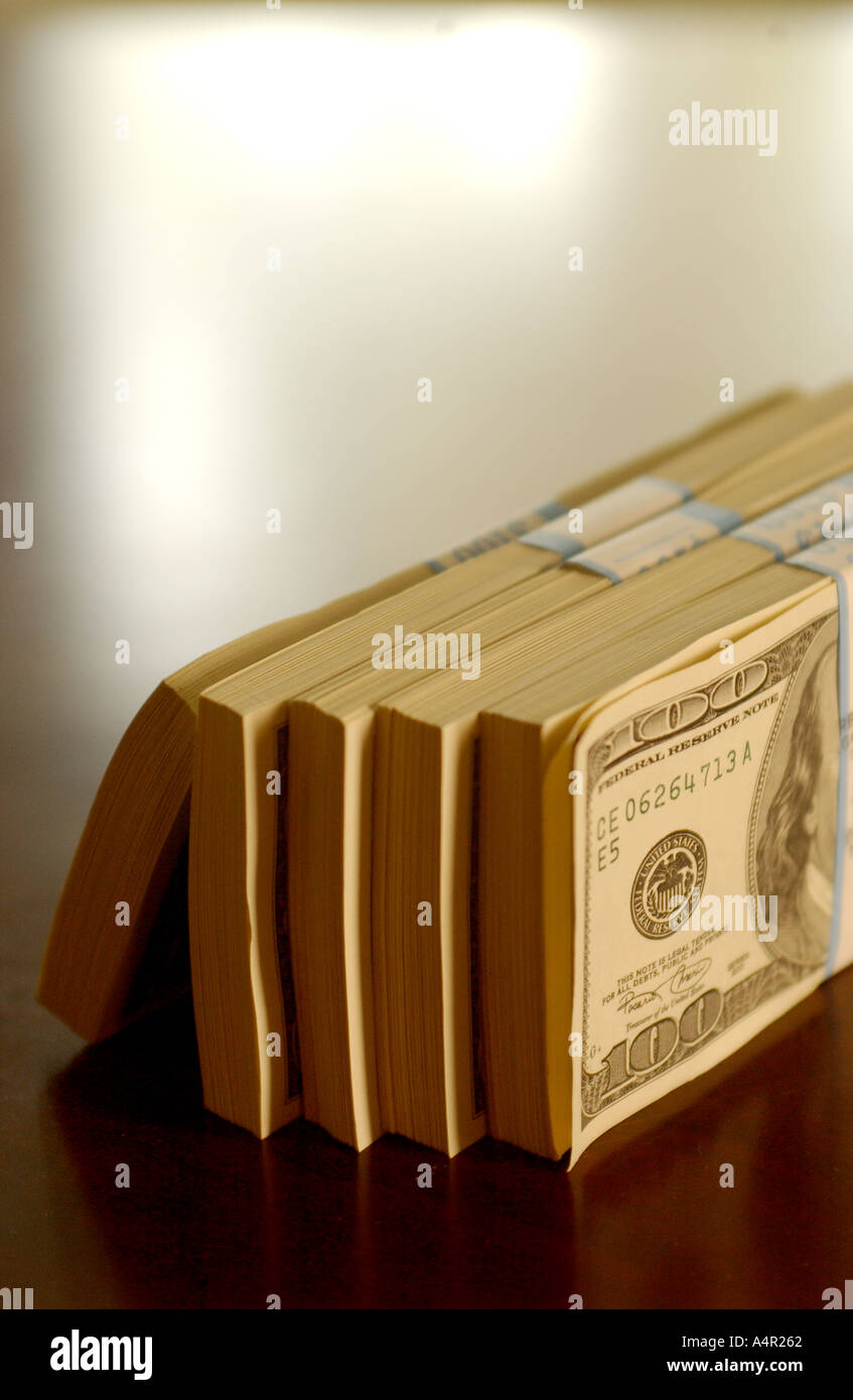 Color image of a banded stack of US currency sitting on a wood table ...