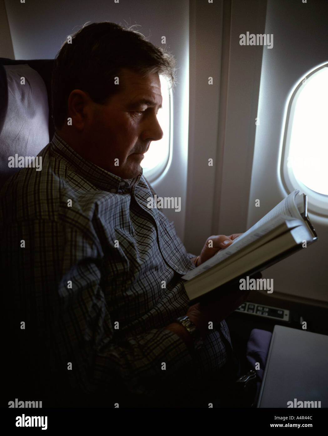man person traveler reading book airplane flight Stock Photo - Alamy