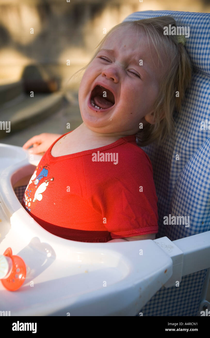 Side profile of a girl crying on a highchair Stock Photo - Alamy