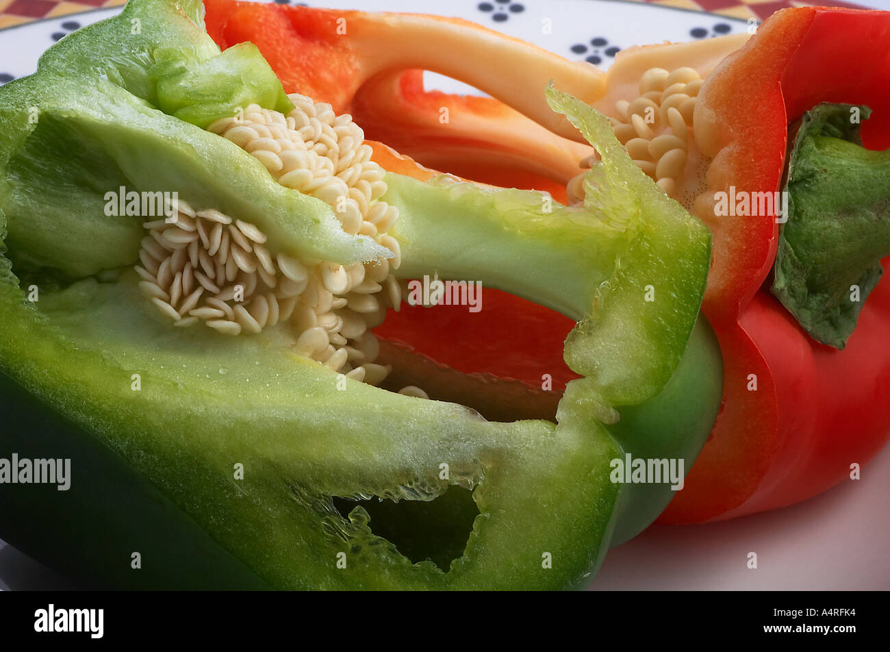 A green and red pepper having been cut open exposing the seed of the ...