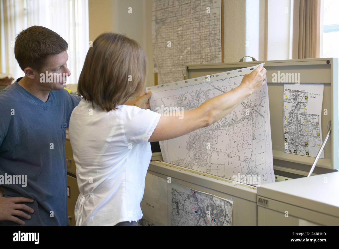 librarian helping a customer lift a map from the reference cabinet file ...