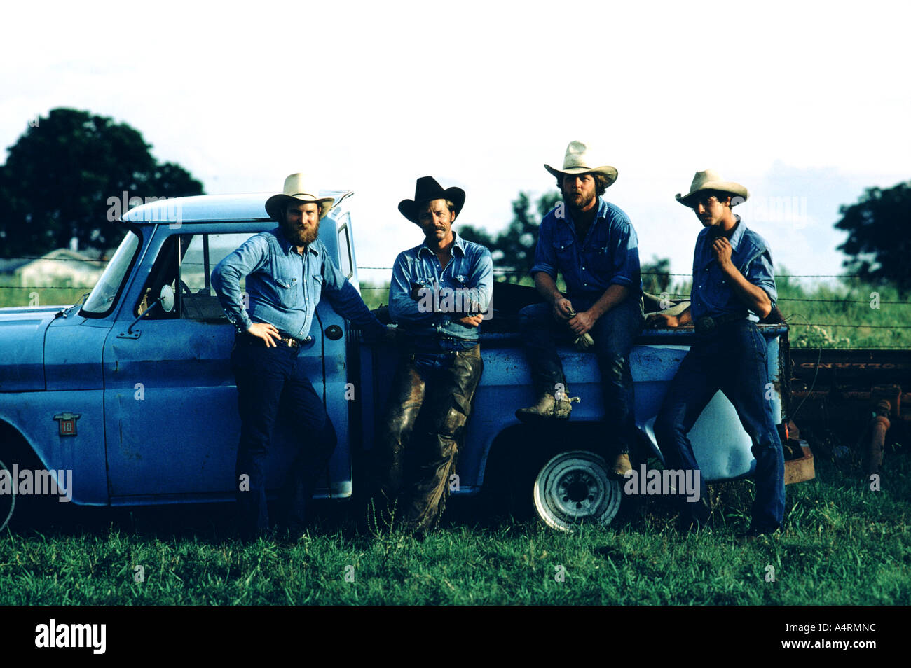 After a long day on a cattle ranch in Texas, several cowboys relax by a ...