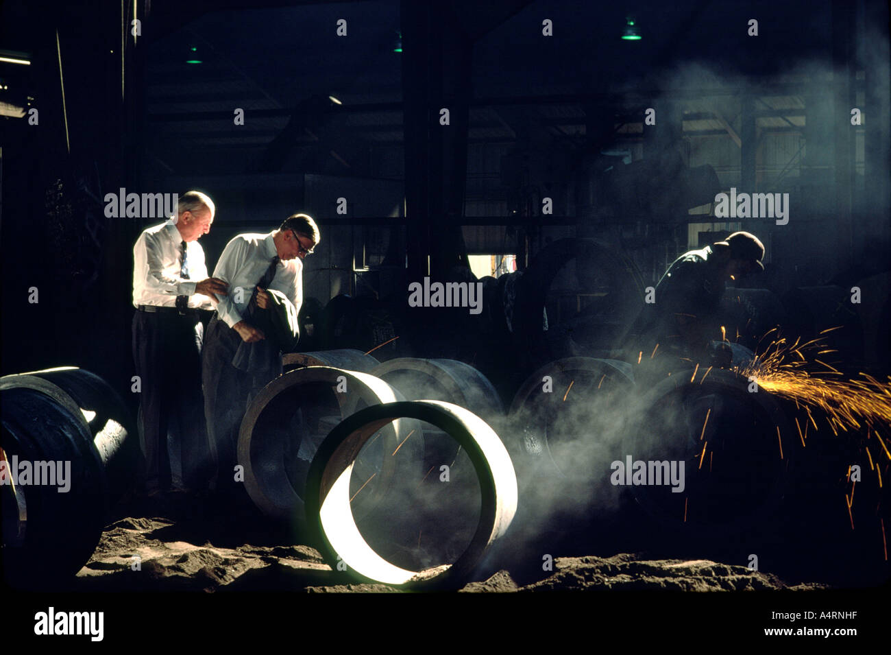 A banker and his client observe the manufacturing process at the client ...