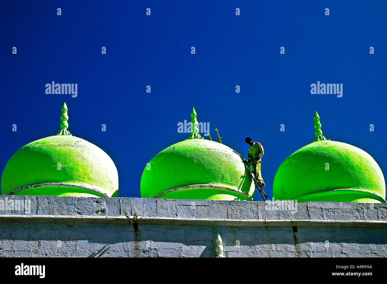 SUB98550 Painter painting with colour green the minarets of a Mosque ...