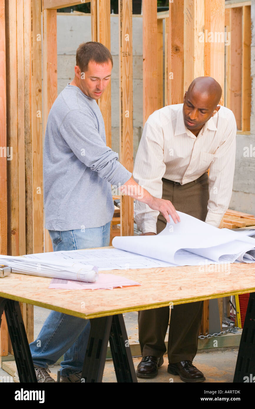 Young men looking at blueprints at construction site Stock Photo - Alamy