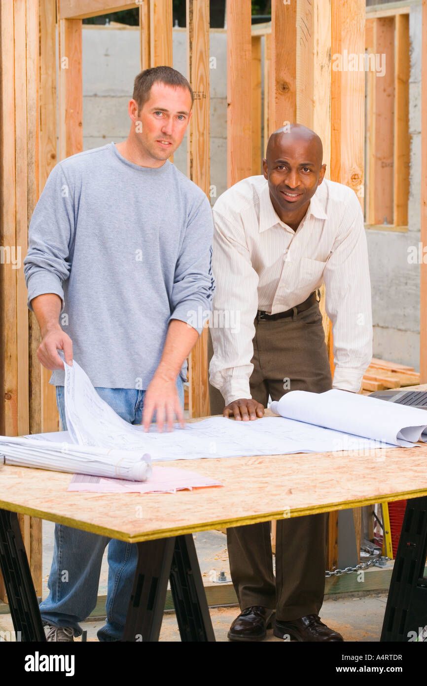 Portrait of young men with blueprints at construction site Stock Photo ...