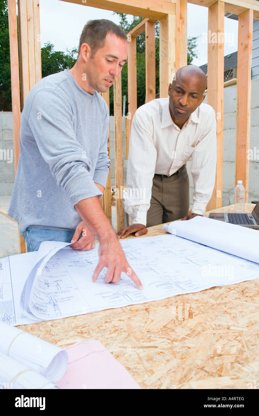 Young men looking at blueprints at construction site Stock Photo - Alamy