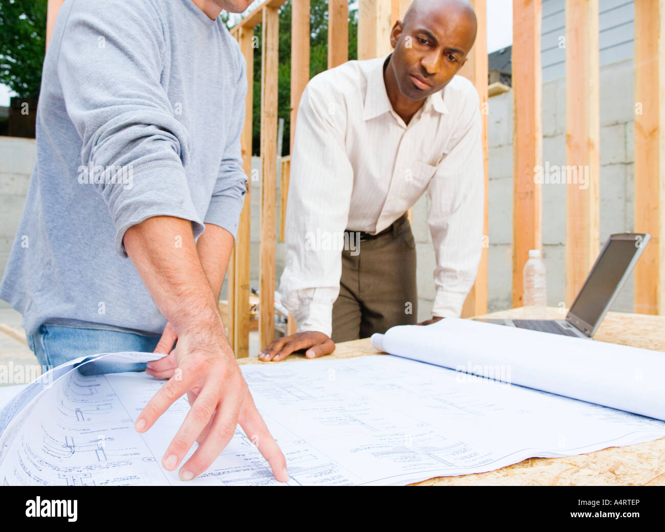 Two men looking at blueprints at construction site Stock Photo - Alamy
