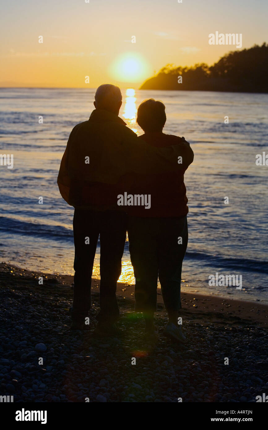 Silhouette of couple watching sunset on beach Stock Photo - Alamy