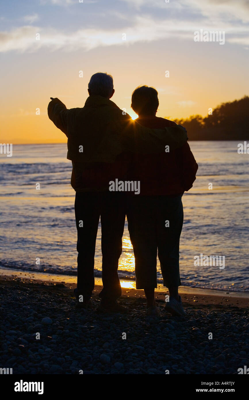 Silhouette of couple watching sunset on beach Stock Photo - Alamy