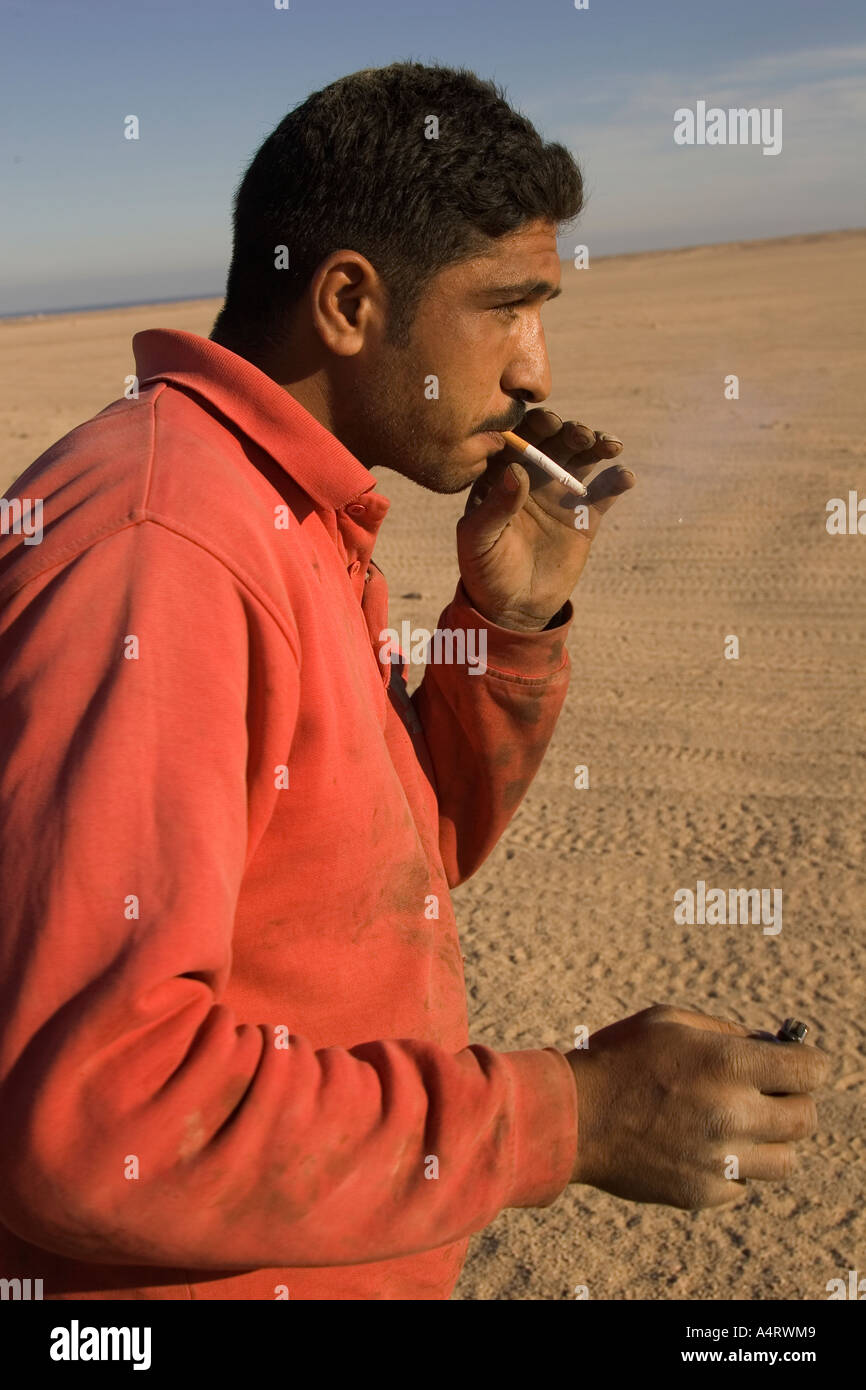 Side profile of a mid adult man standing in the desert smoking a ...