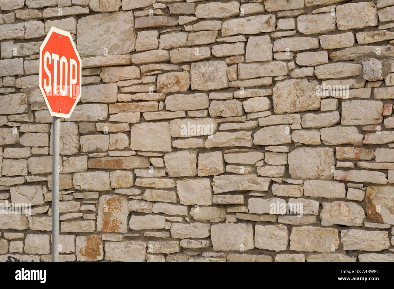 Stop sign near a stone wall Stock Photo - Alamy