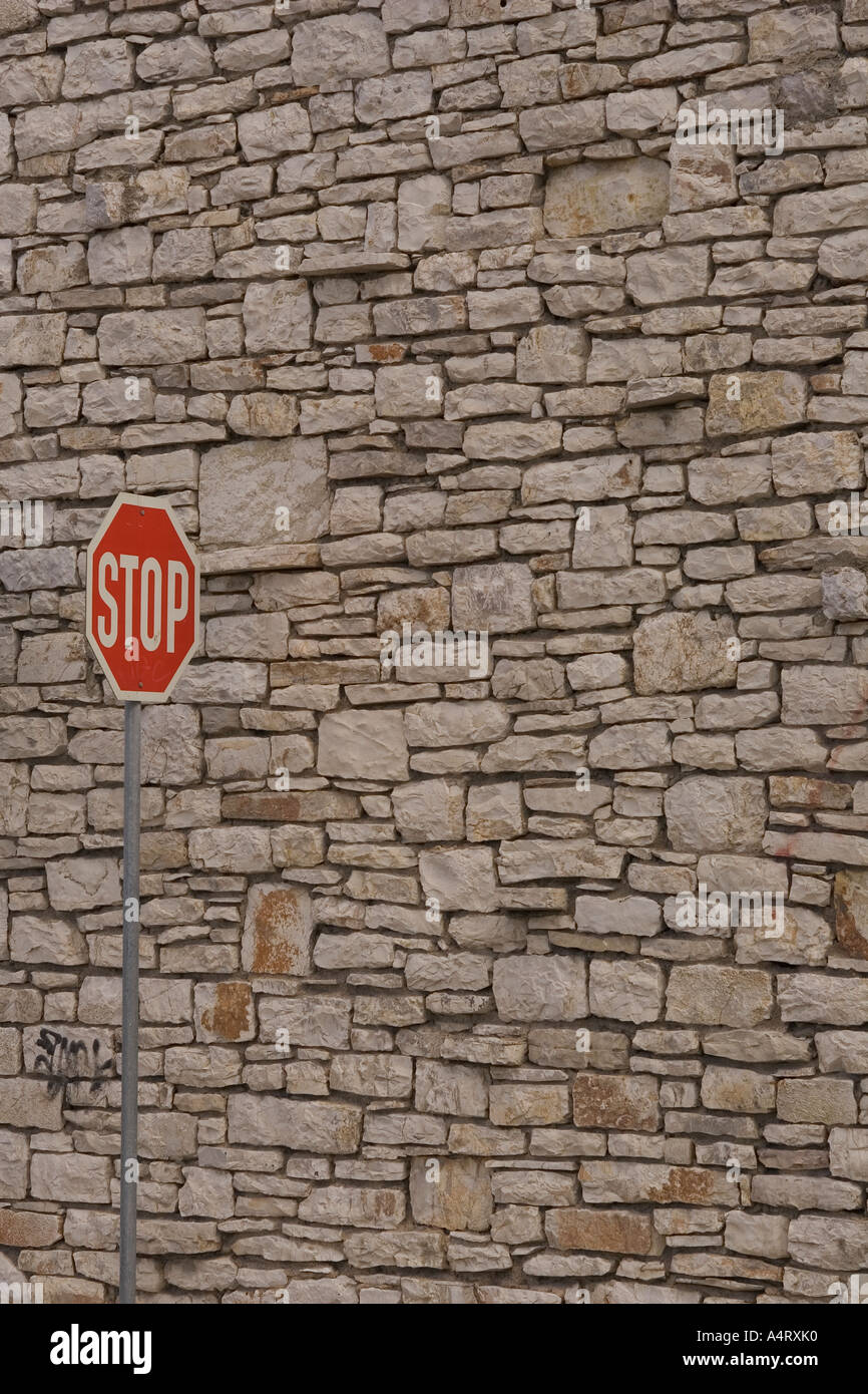 Stop sign in front of a stone wall Stock Photo - Alamy