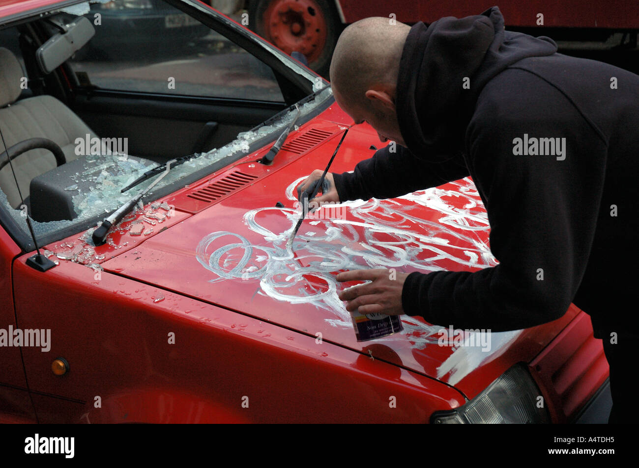 Graffiti artist at work painting on a wrecked car Stock Photo - Alamy