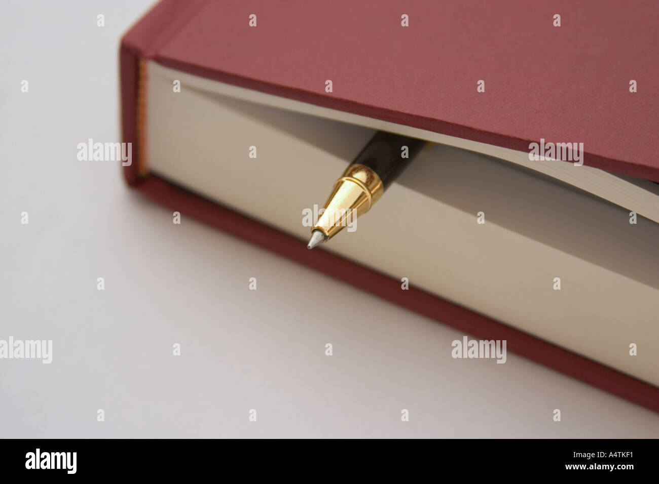 pen wedged between a red book concept knowledge education homework ...